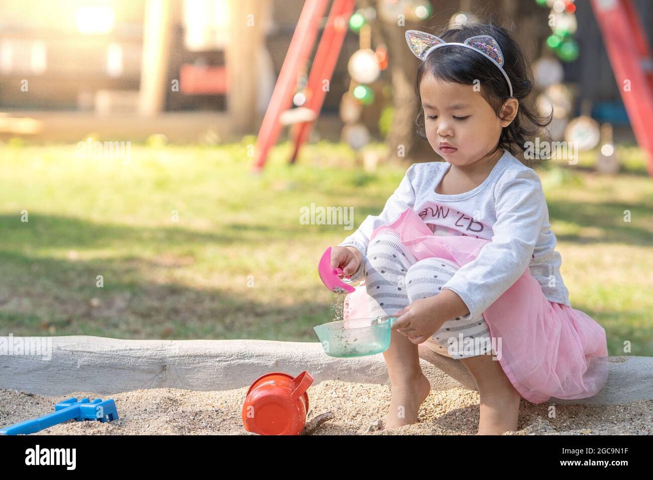 Cute Asian small girl playing in a sandpit Stock Photo - Alamy