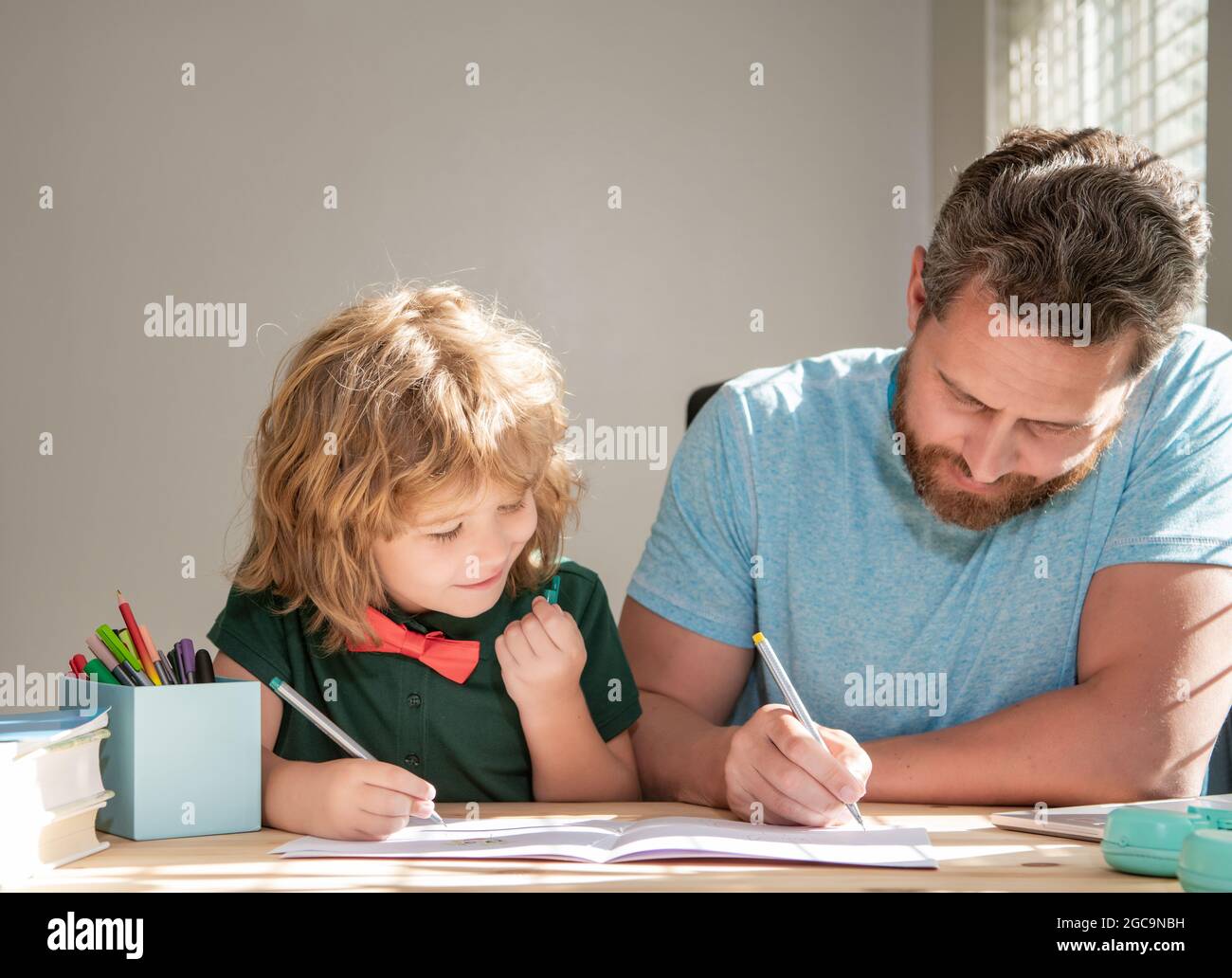 parenthood. concentrated father and son writing at home. family day ...