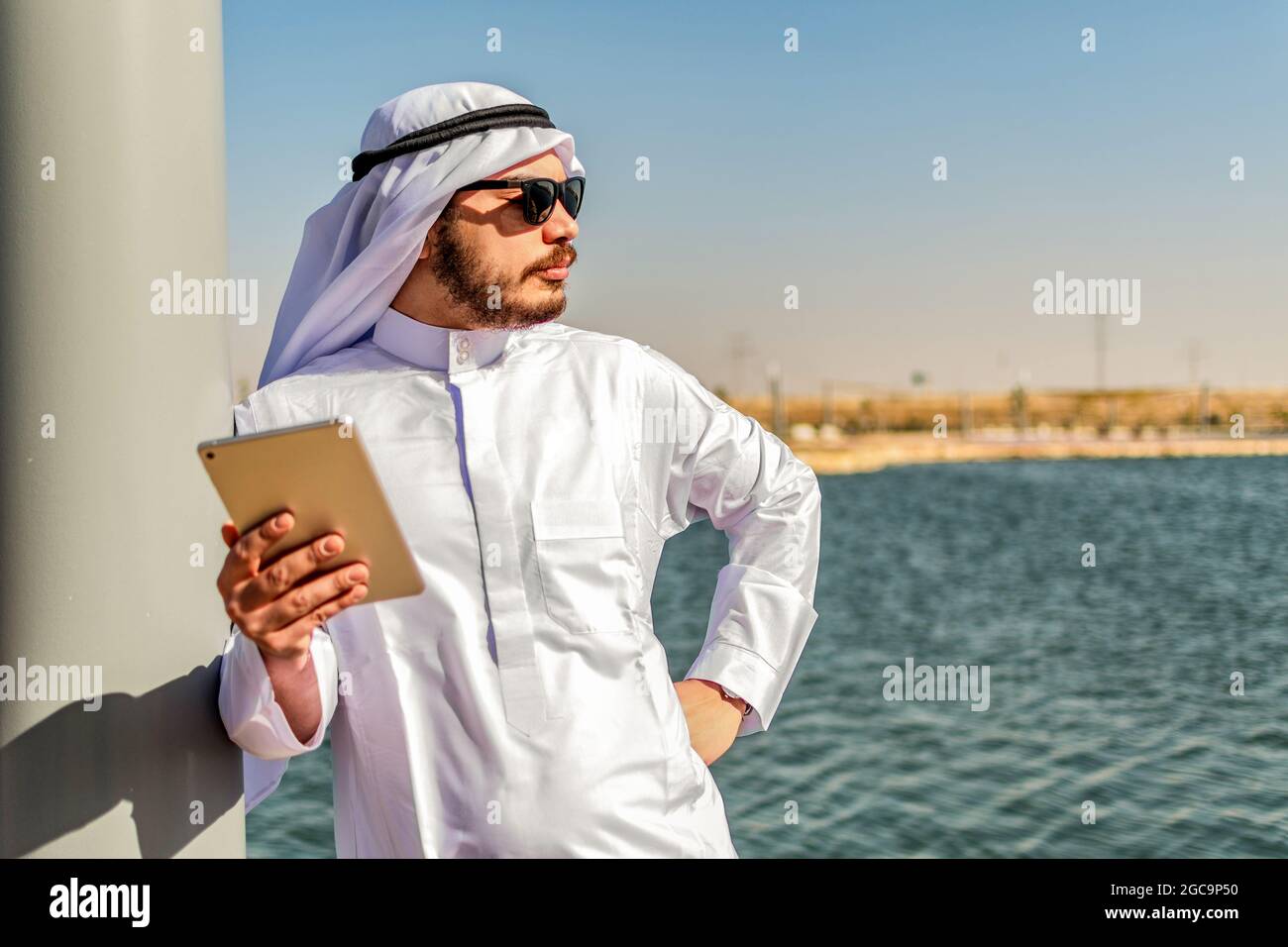 Portrait of a concentrated Islamic male, in traditional clothing, using ...