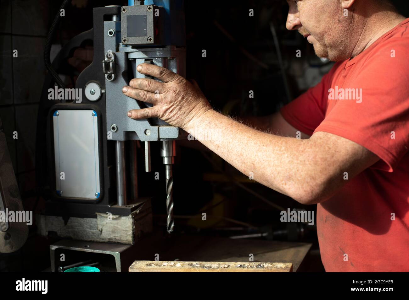 A man installs a drilling machine. The guy in the workshop is setting ...