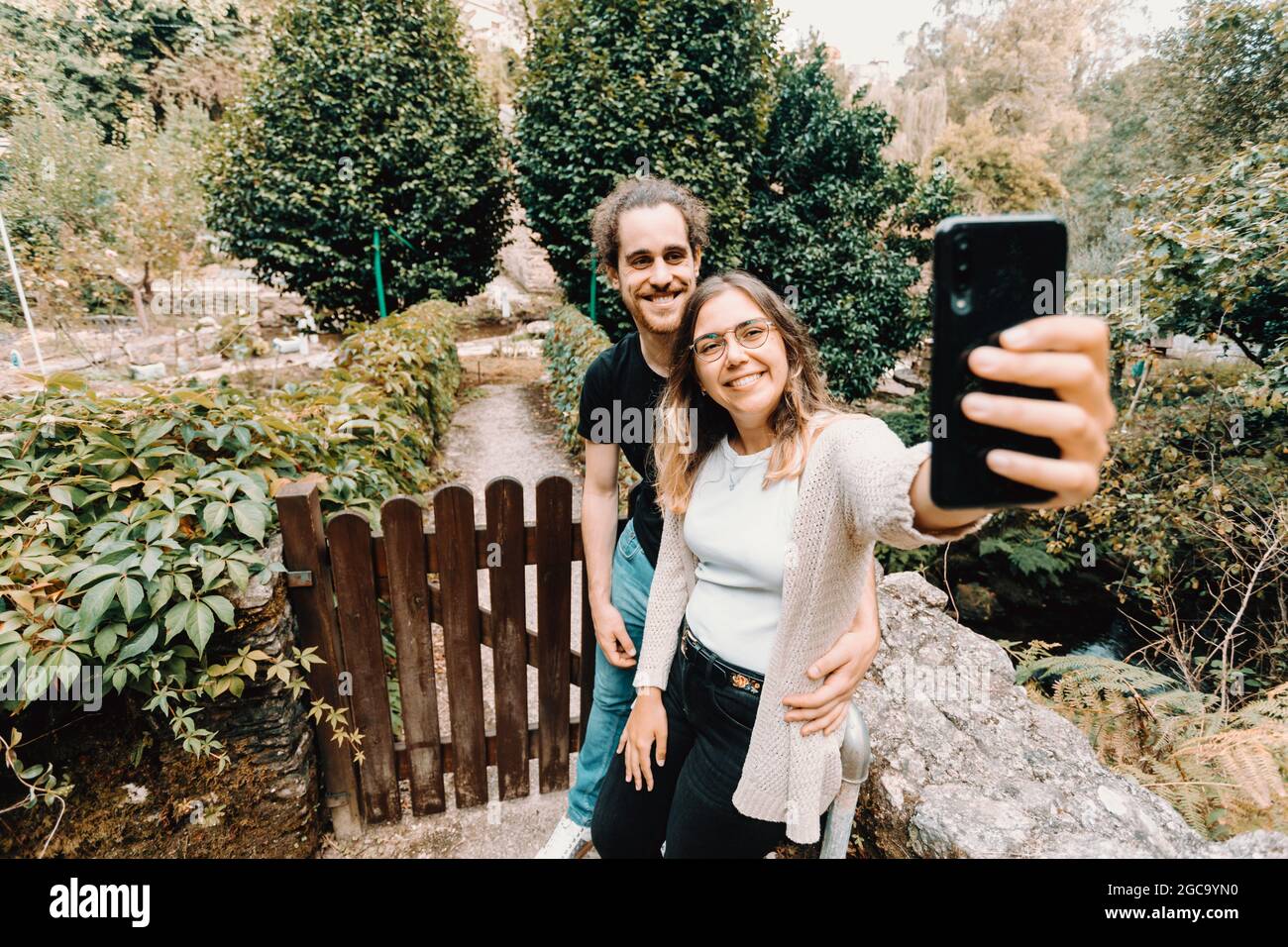 Closeup shot of a young Caucasian couple taking selfie in a garden with ...