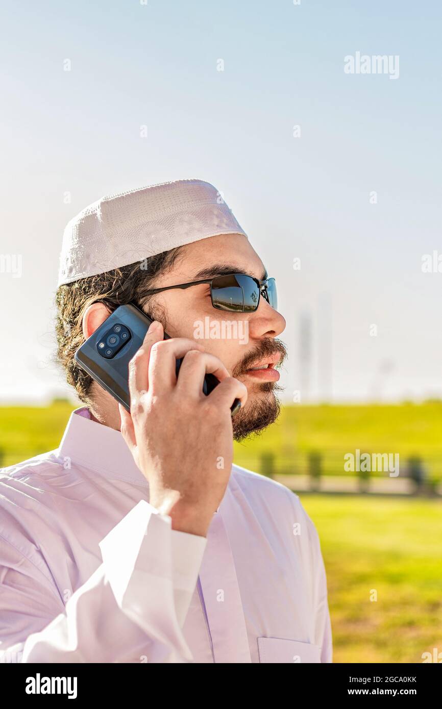 Vertical shot of an Arab male talking on the phone, in traditional ...