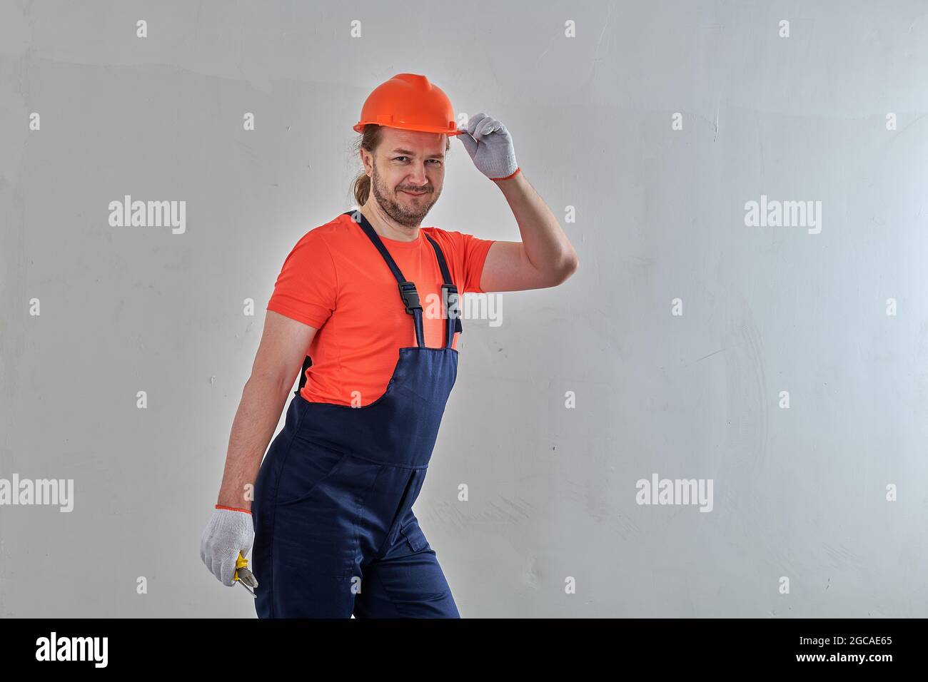 orange hard hat repair master stands against white wall background ...