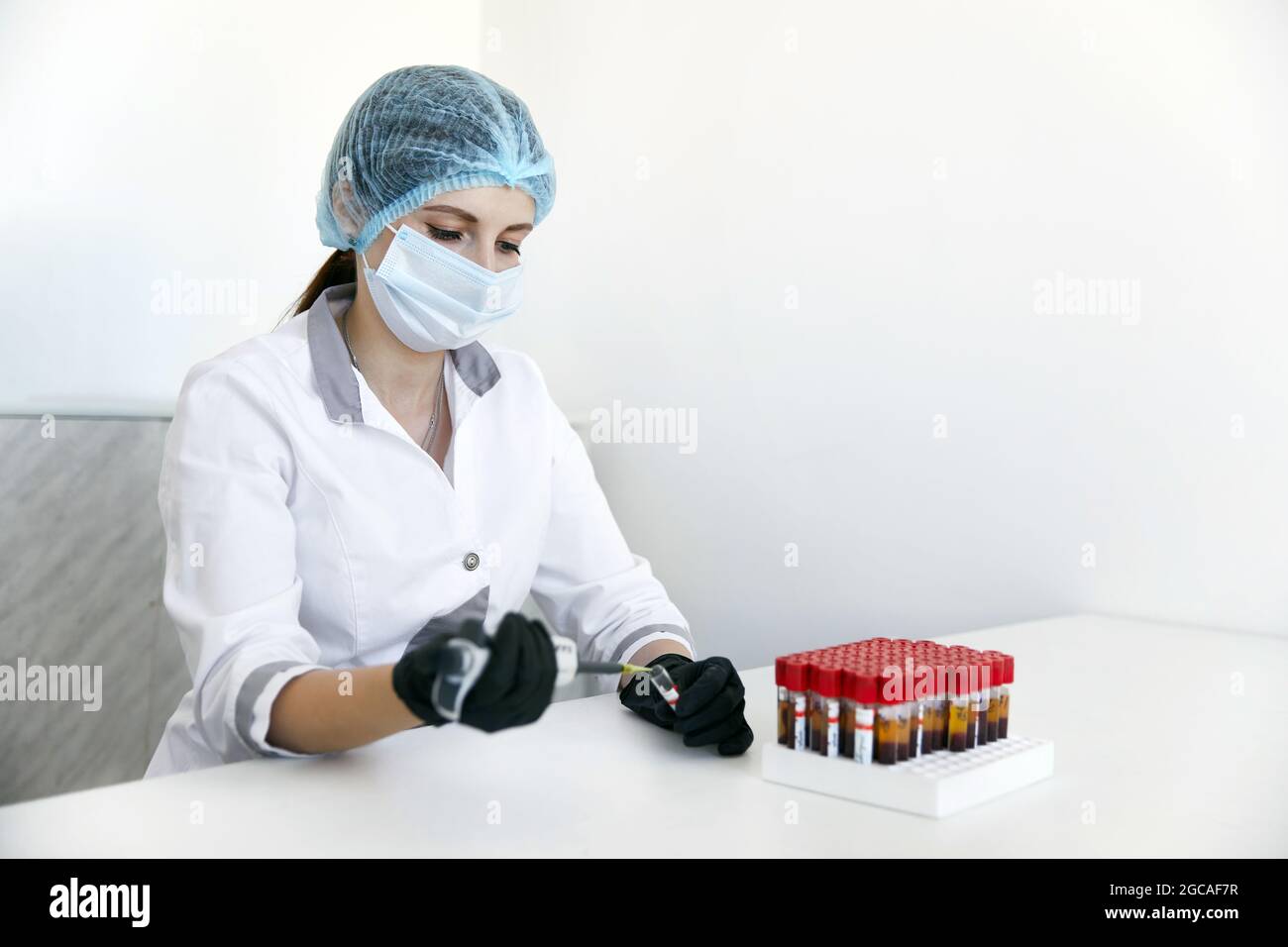 lab technician with tube of blood sample and rack with other samples ...