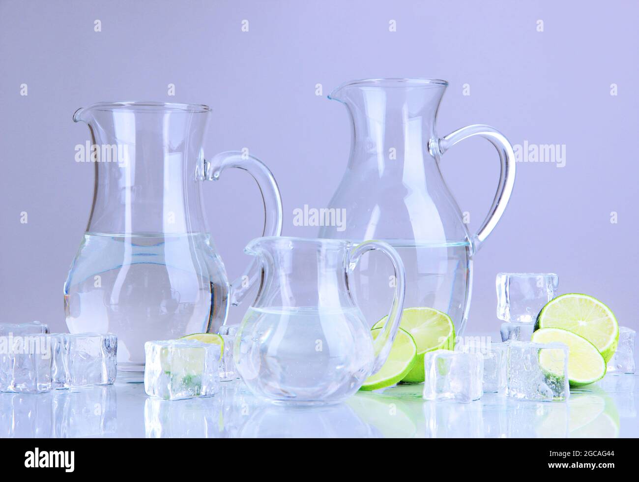 Glass pitchers of water with ice and lime on grey background Stock ...