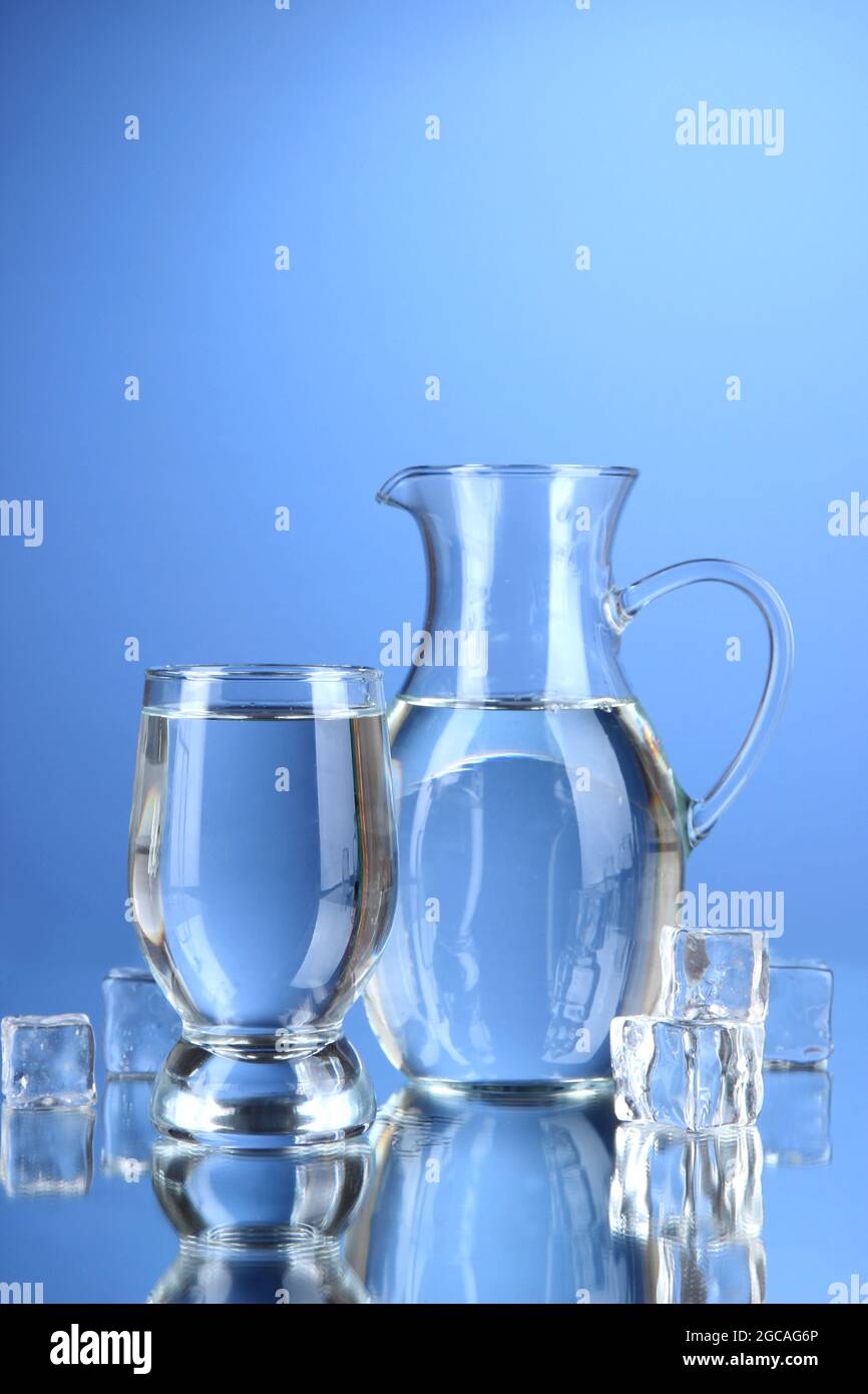 Glass pitcher of water and glass on blue background Stock Photo - Alamy
