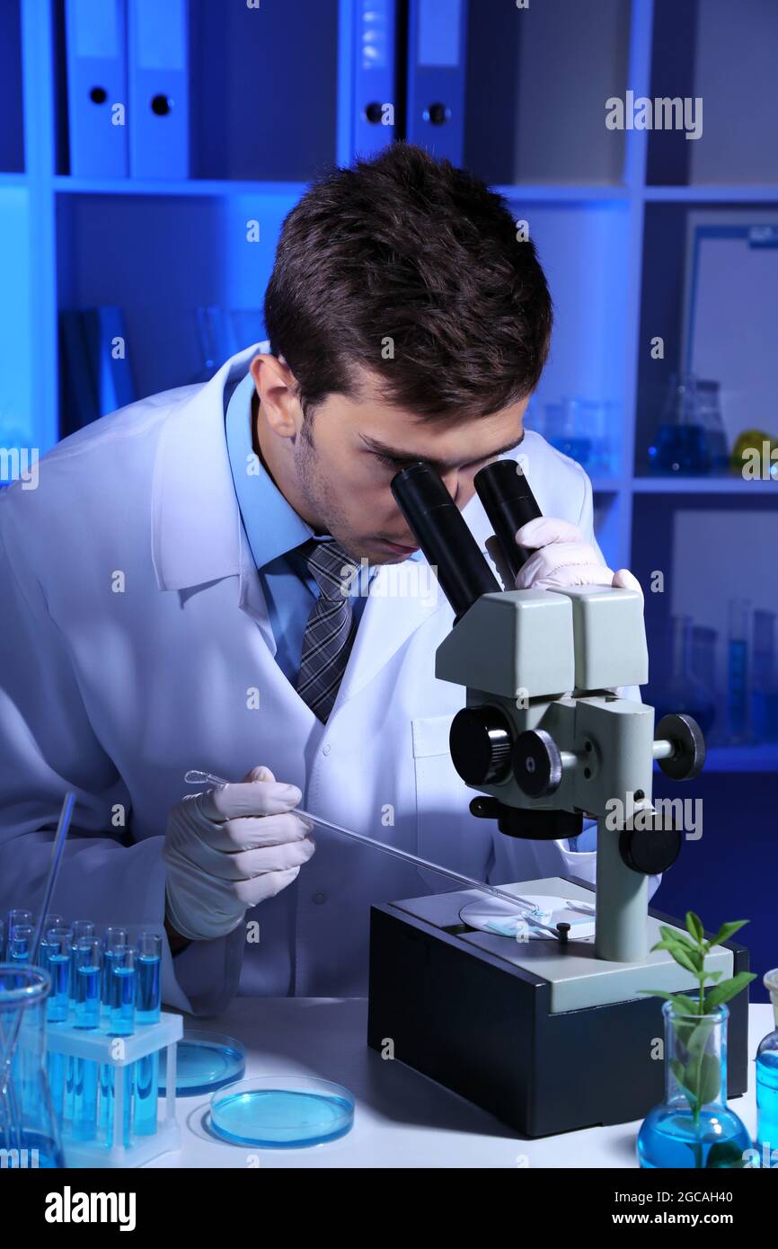 Young laboratory scientist looking at microscope in lab Stock Photo - Alamy