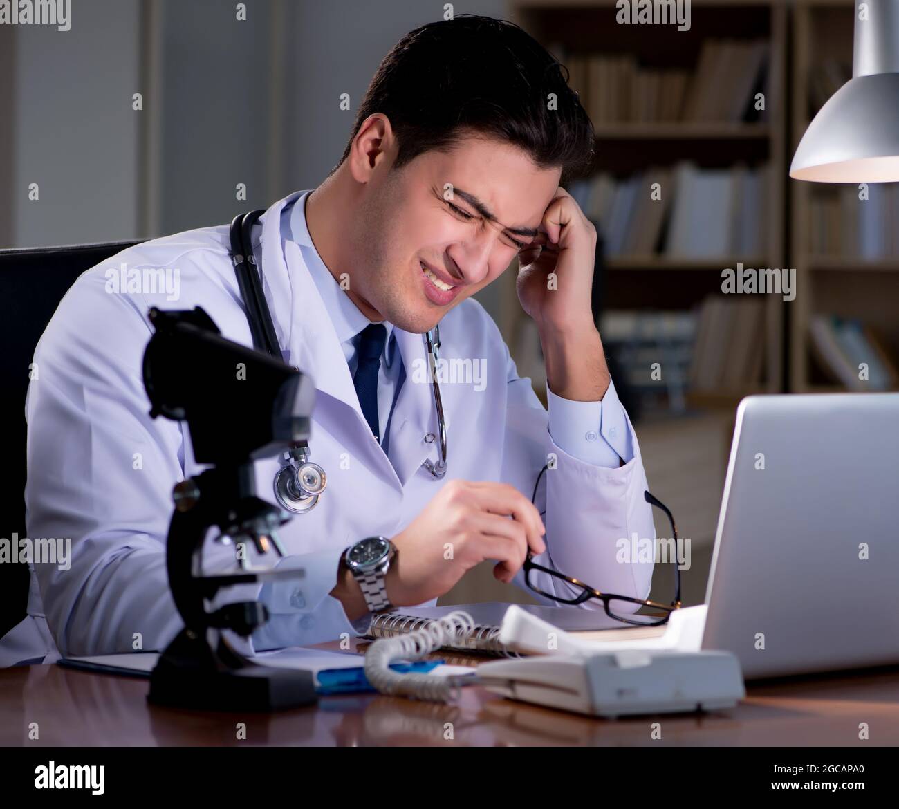 The young doctor working late in the office Stock Photo - Alamy