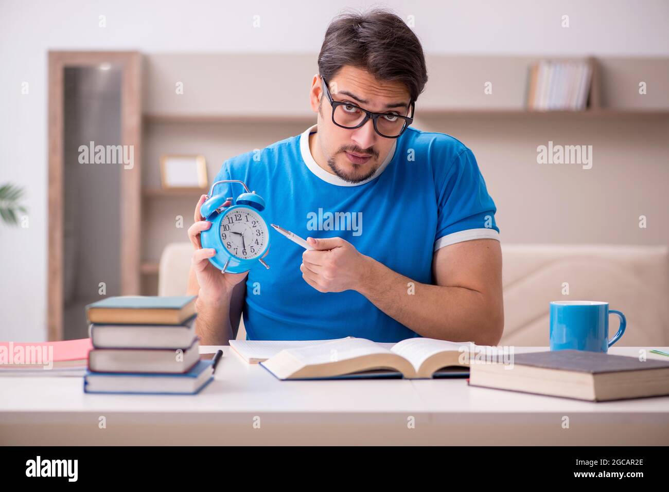Young student studying at home in time management concept Stock Photo ...