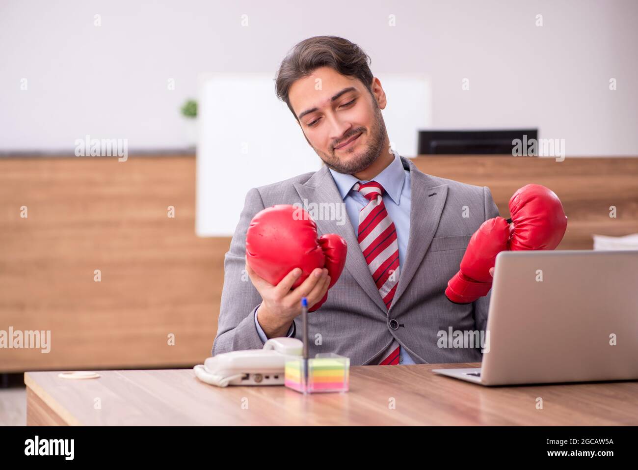 Young businessman employee wearing boxing gloves at workplace Stock ...