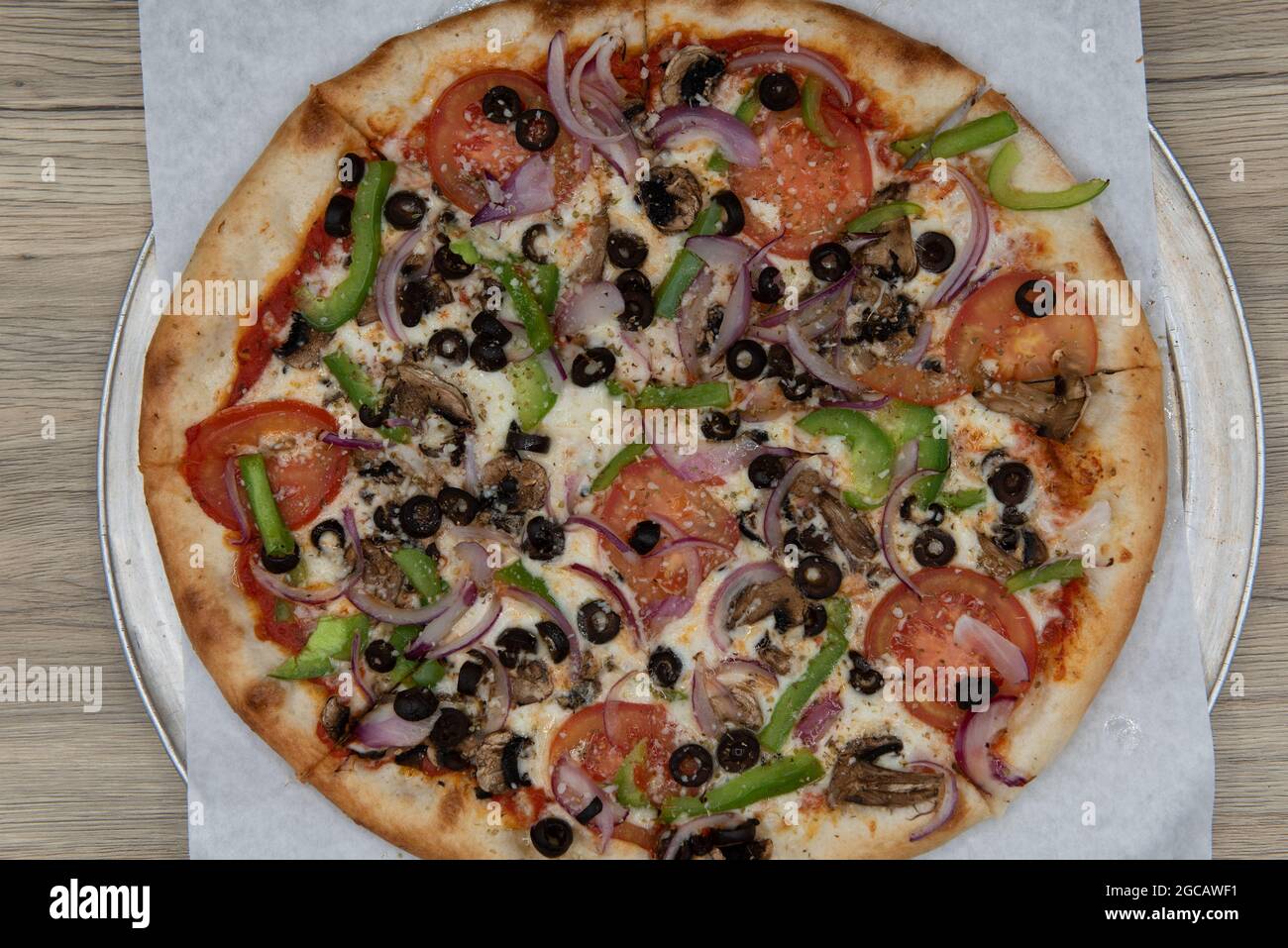 Overhead view of vegetarian pizza loaded with vegetable toppings and a ...