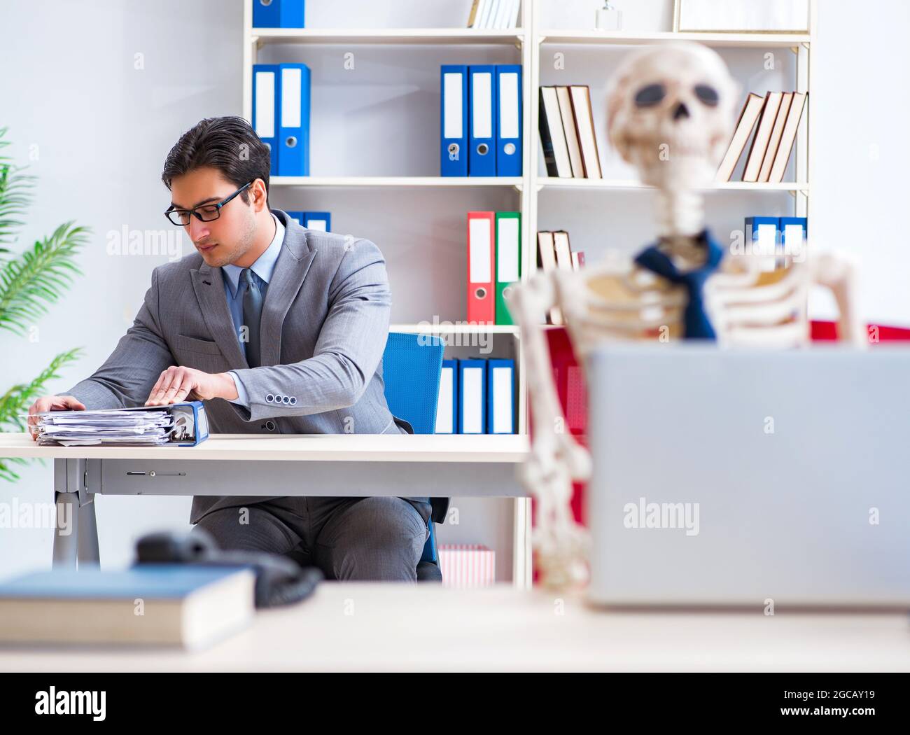 The businessman working with skeleton in office Stock Photo - Alamy
