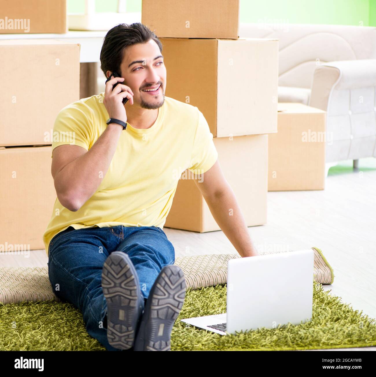 The young handsome man moving in to new house with boxes Stock Photo ...