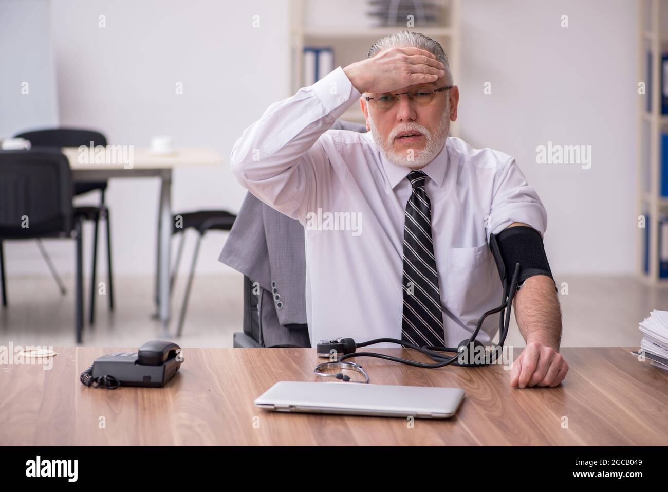 Aged male employee feeling bad in the office Stock Photo - Alamy