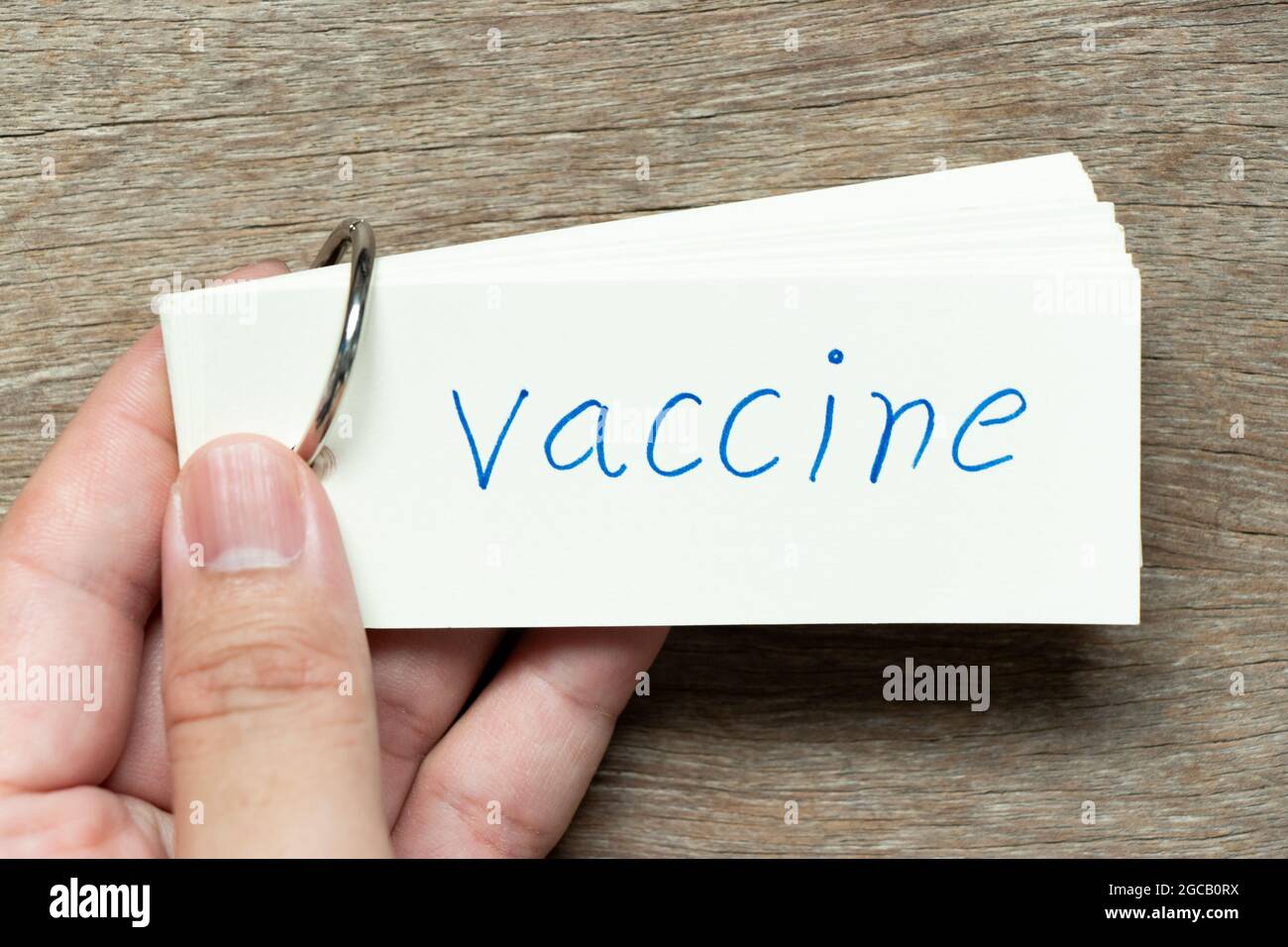 Man hold the flash card with handwriting word vaccine on wood ...