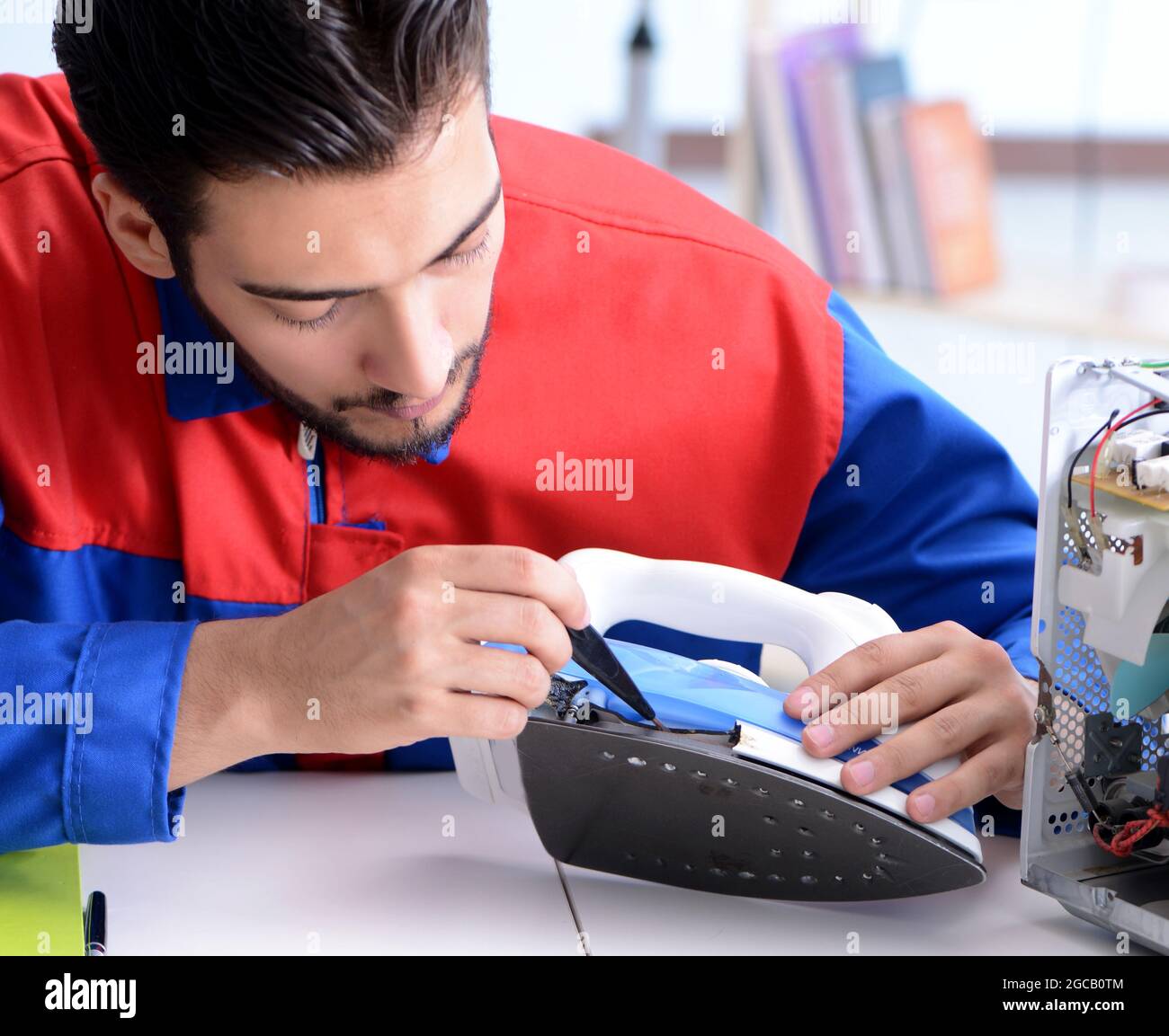 The man repairman repairing iron at service center Stock Photo - Alamy