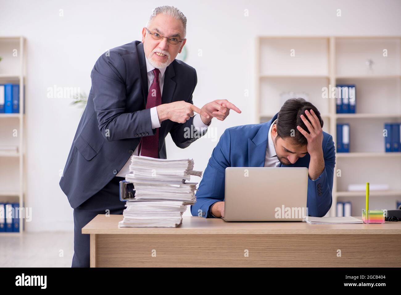 Old boss and young employee in bullying concept Stock Photo - Alamy