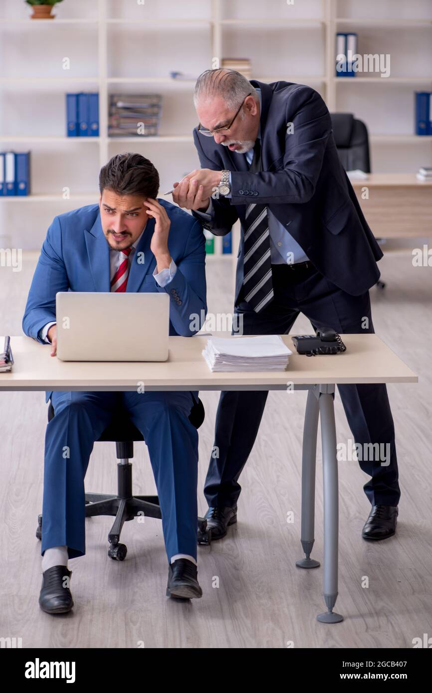 Old boss and young employee in bullying concept Stock Photo - Alamy