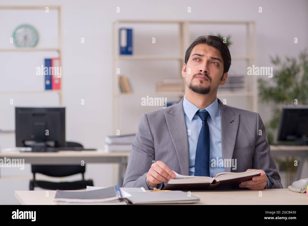 Young businessman employee reading book in the office Stock Photo - Alamy