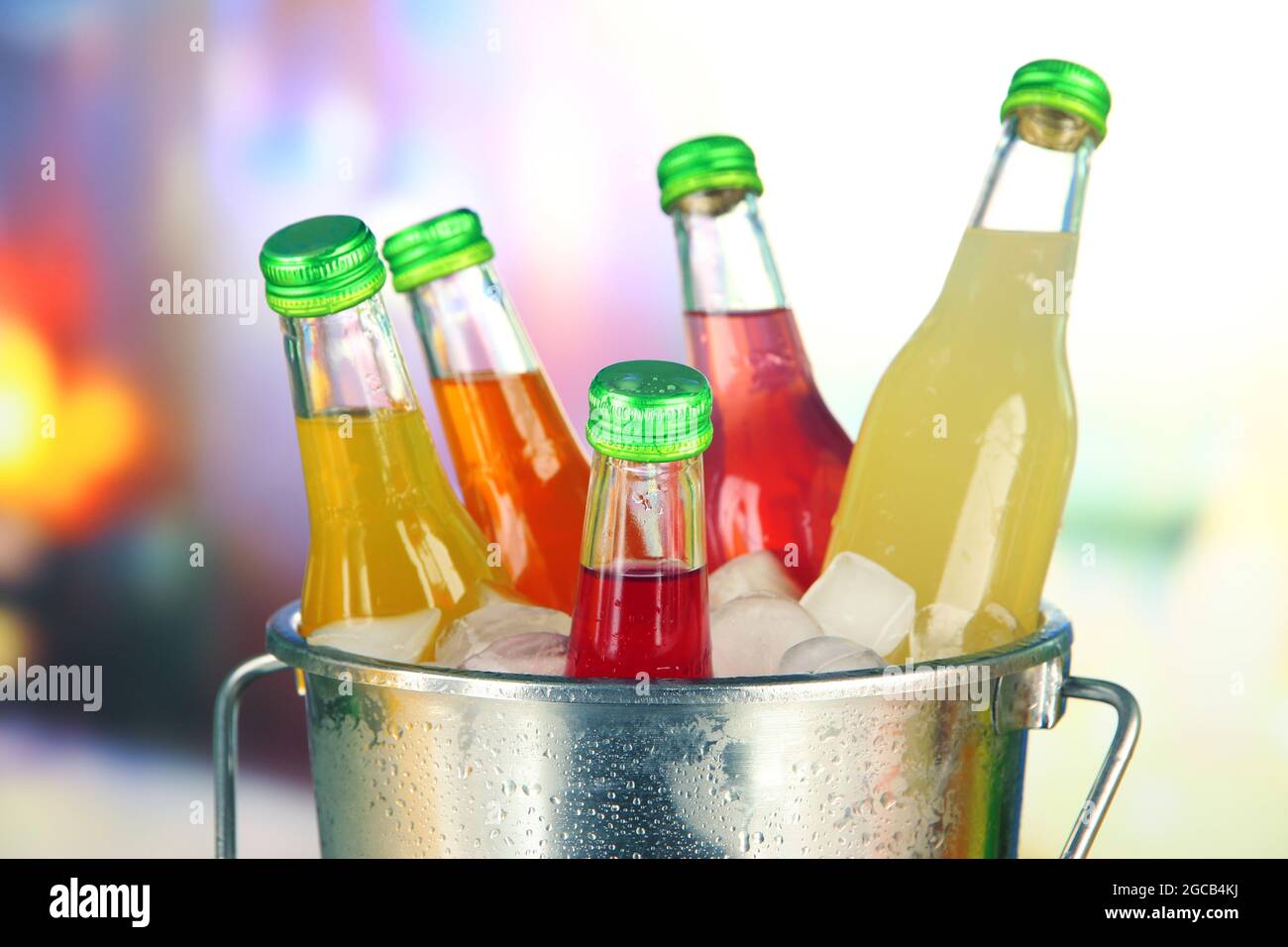 Bottles with tasty drinks in bucket with ice cubes, in bright ...