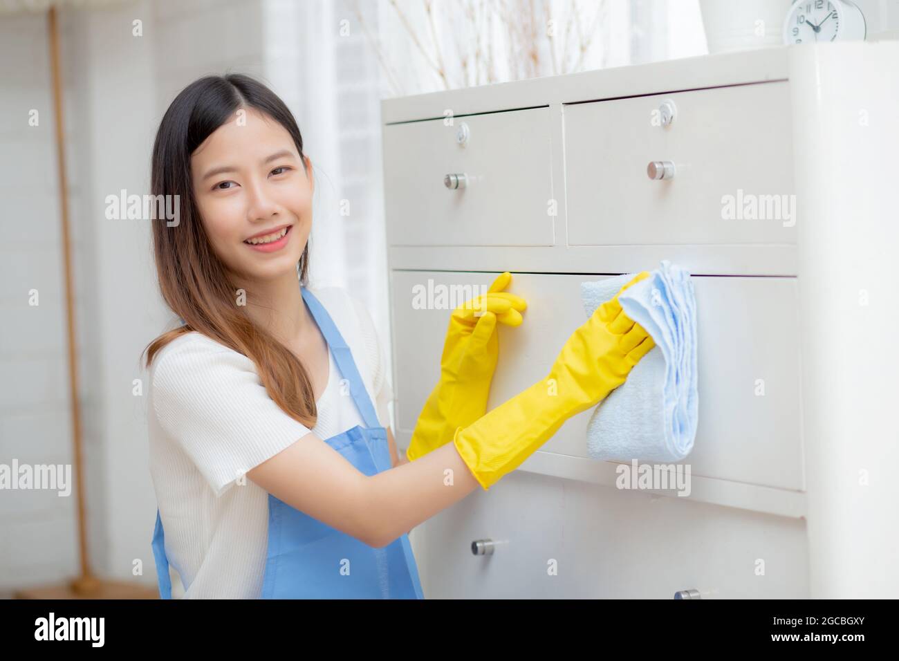 Young asian woman in gloves cleaning home in room, housekeeper is wipe ...