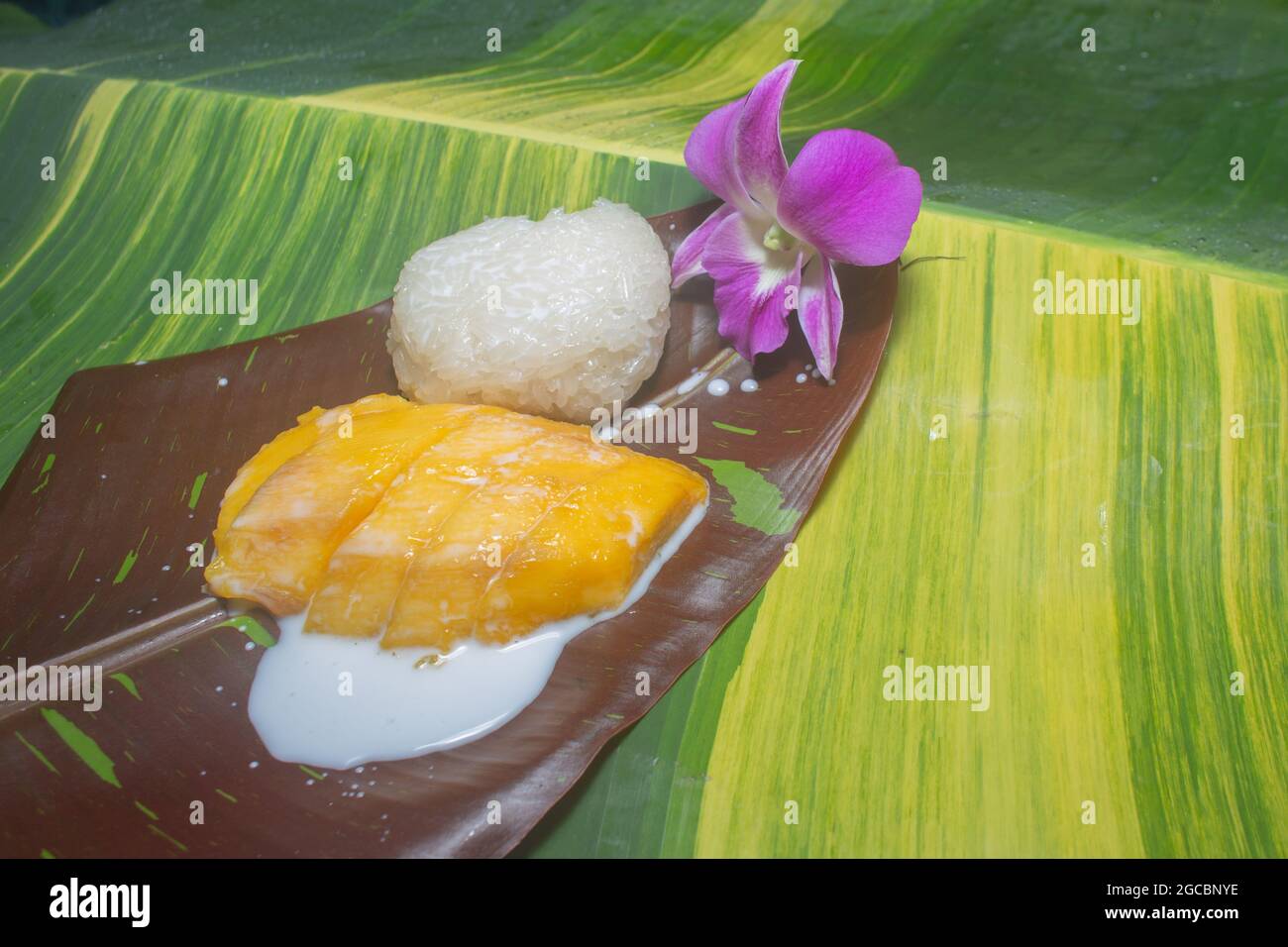 Mango sticky rice served on a spotted banana leaf by the pool. speckled ...