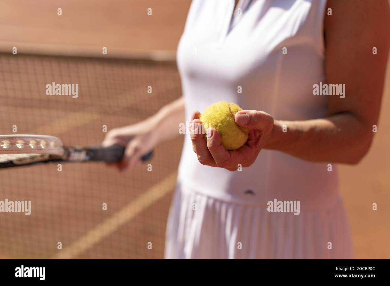 A closeup shot of a female tennis player holding a tennis ball and a ...