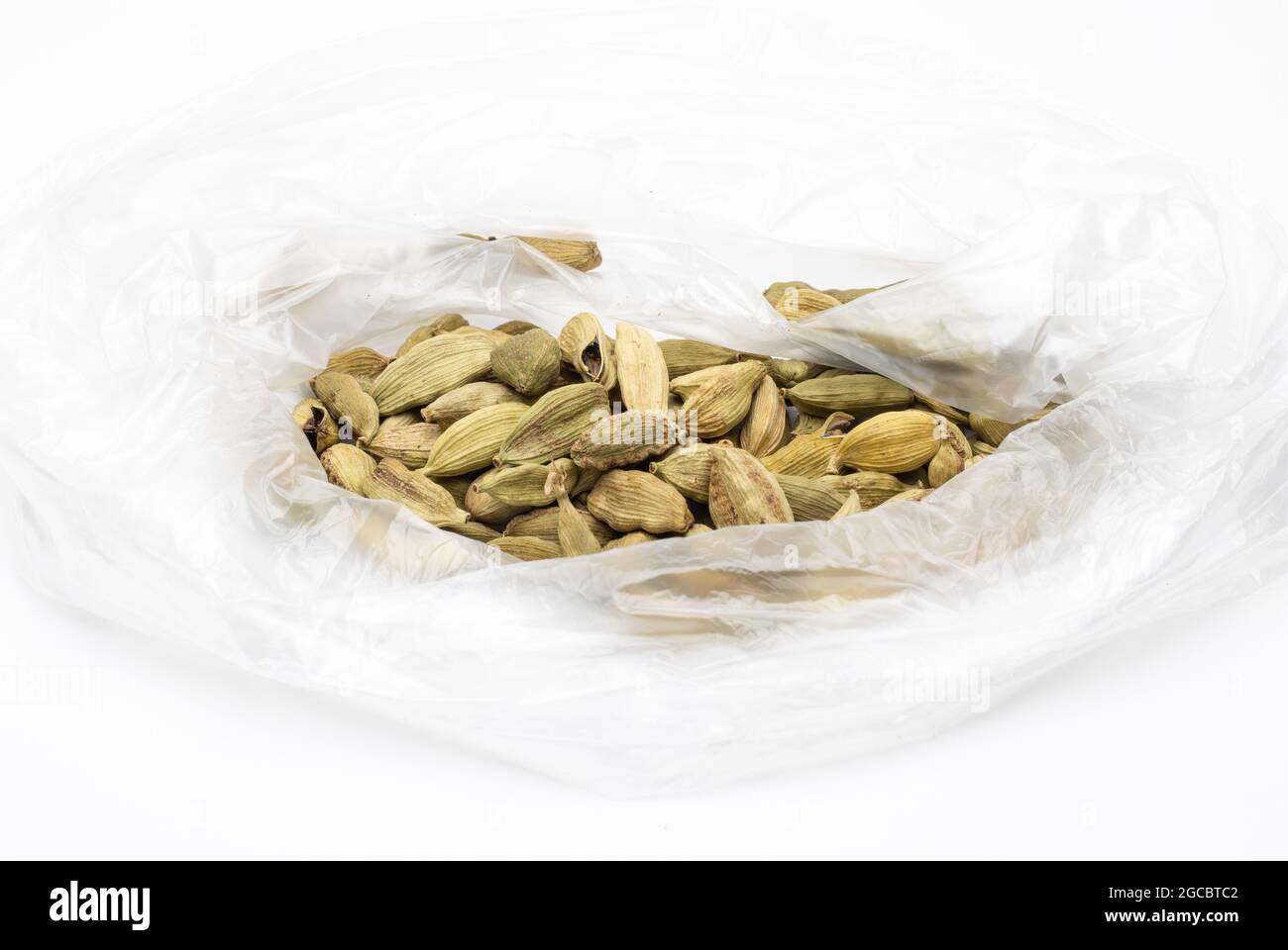 Dried cardamom inside of a transparent white polybag on isolated white ...