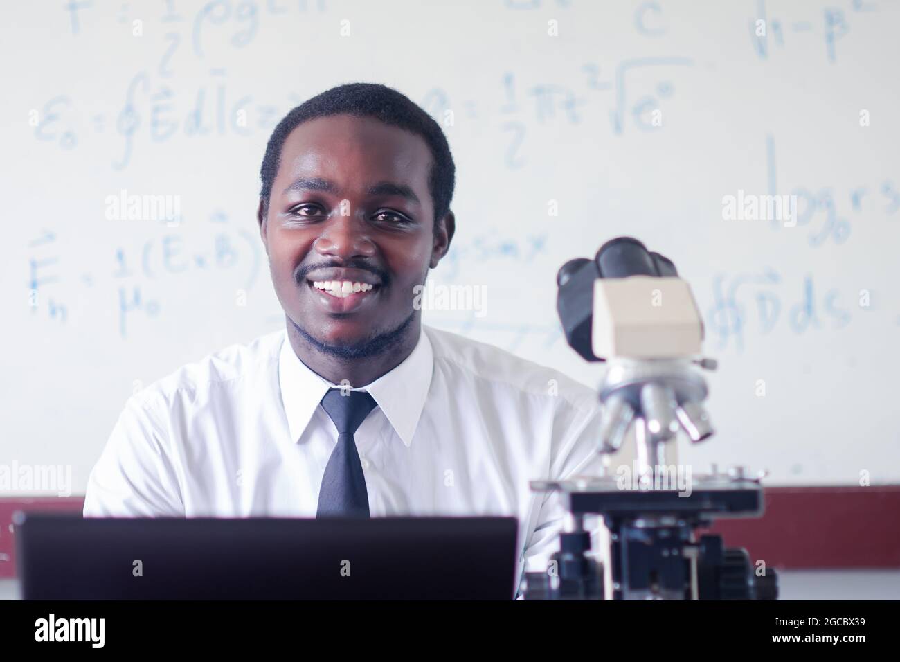 African scientist teacher is teaching science classes with using ...