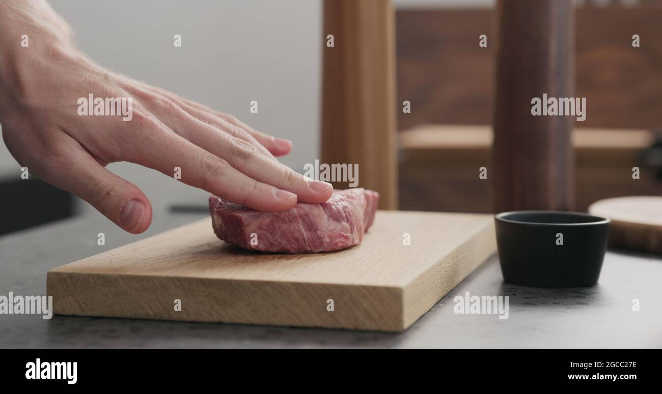 Man hand put raw ribeye steak on oak wood board, wide photo Stock Photo ...