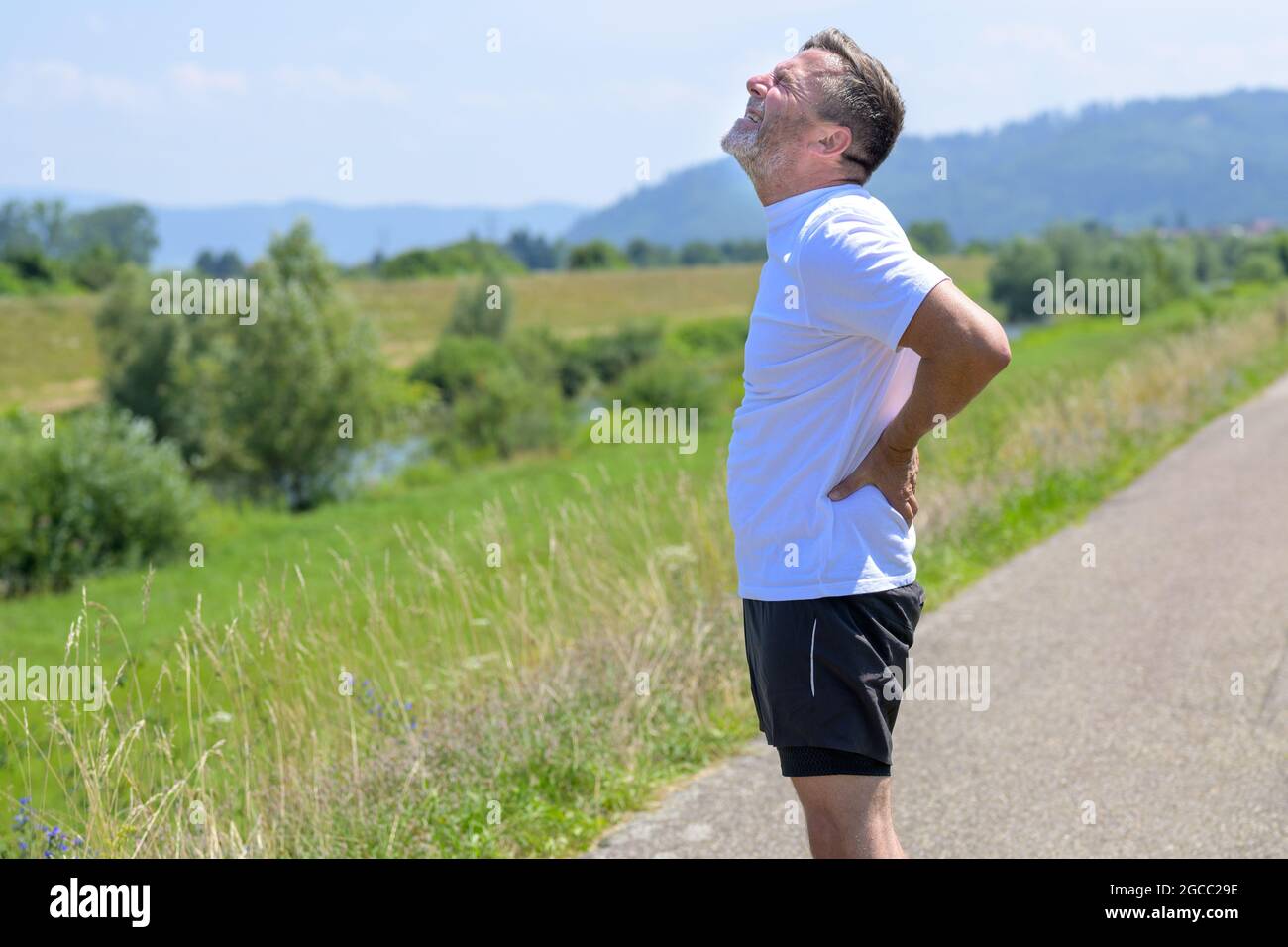 Middle-aged man suffering from acute back pain clutching his lower back ...