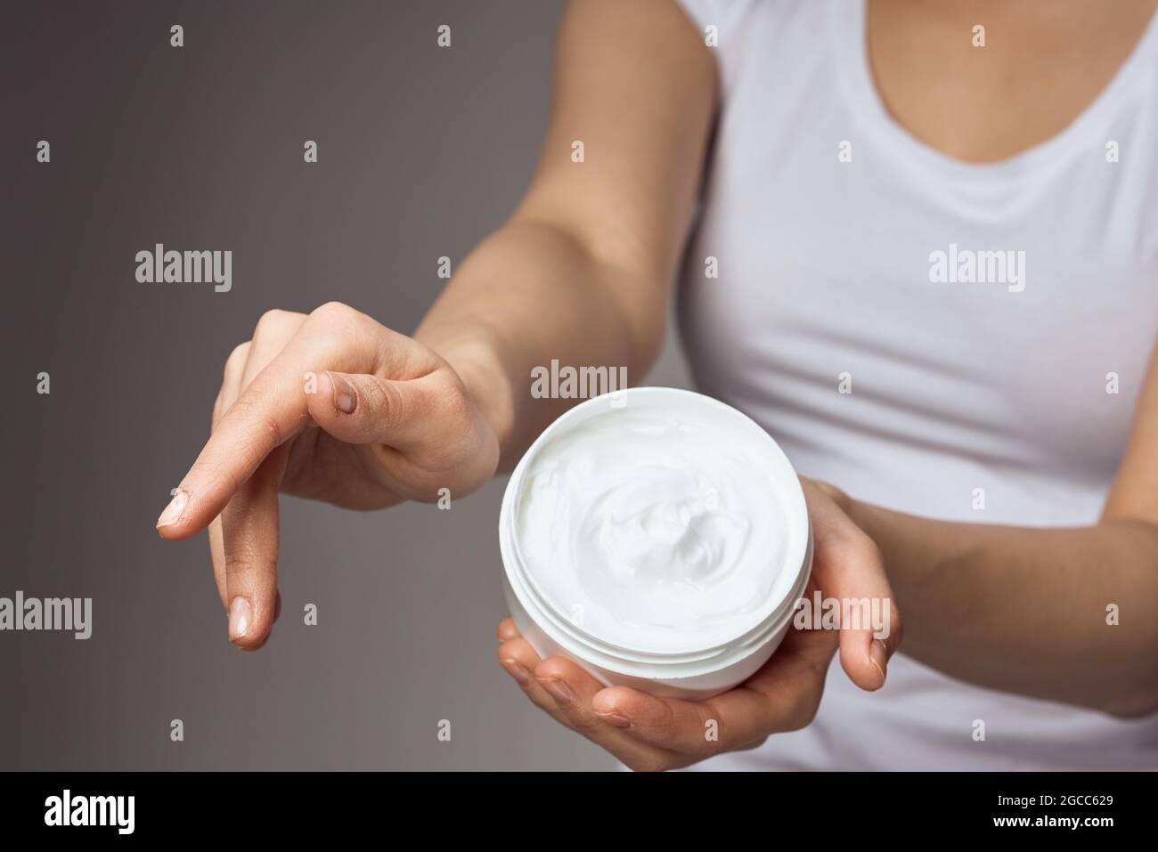 woman in white t-shirt holds cream in hands skin care moisturizing ...