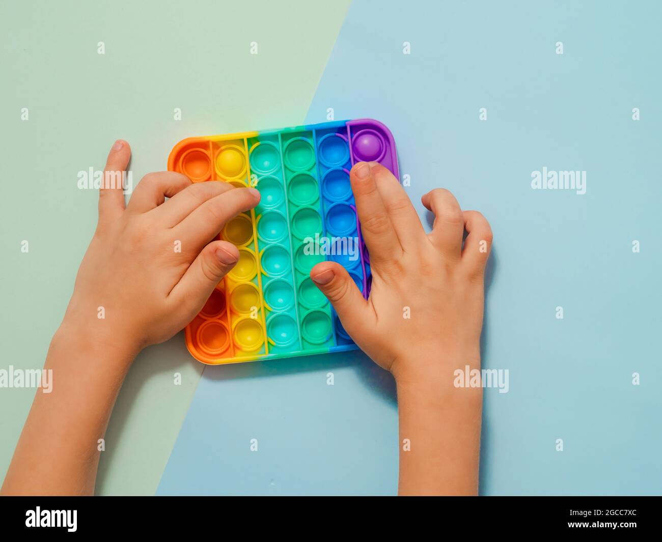 Kid hands play popit toy, top view over two-shadows blue background ...