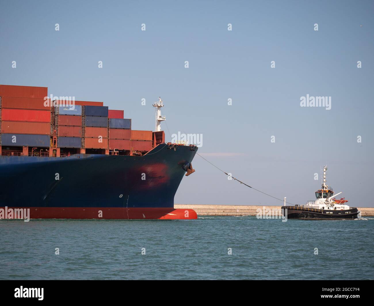 Large Container Ship Towed into Port by a Small Tugboat Stock Photo - Alamy