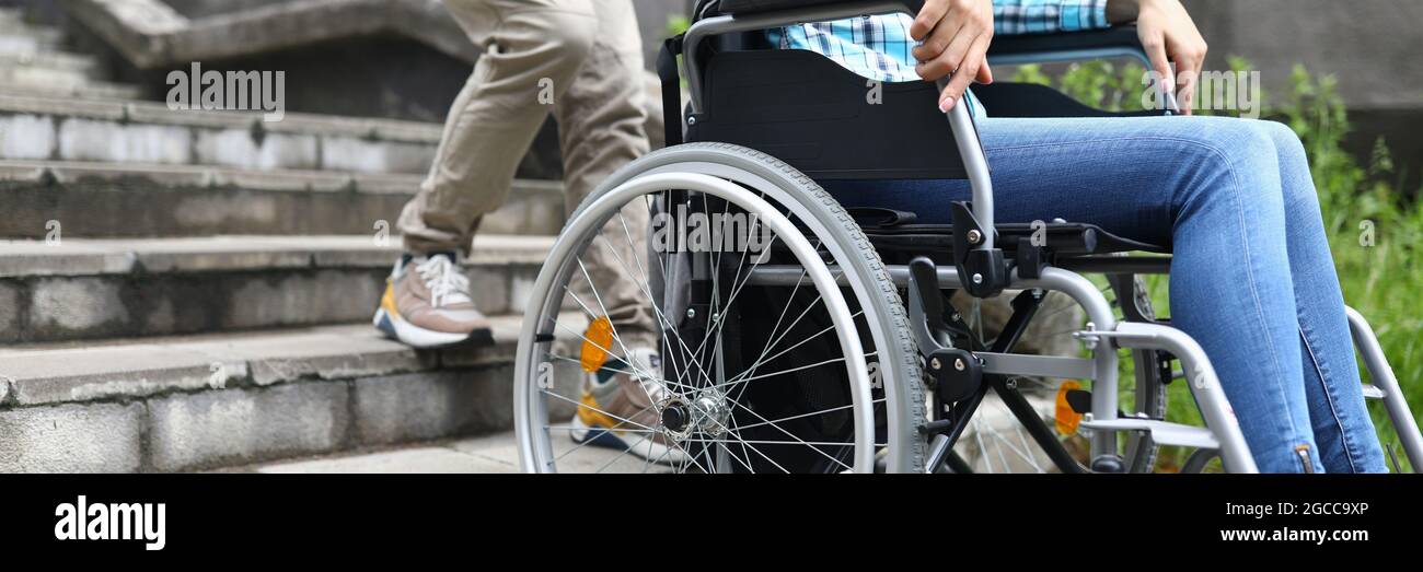 Man tries to drag wheelchair with woman onto stairs Stock Photo - Alamy