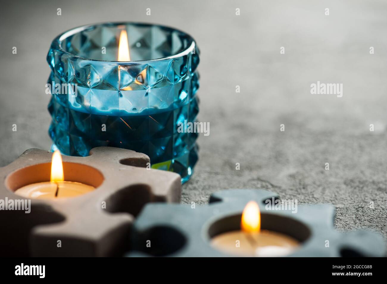Candlesticks with burning candles on stone background. Blue tint ...