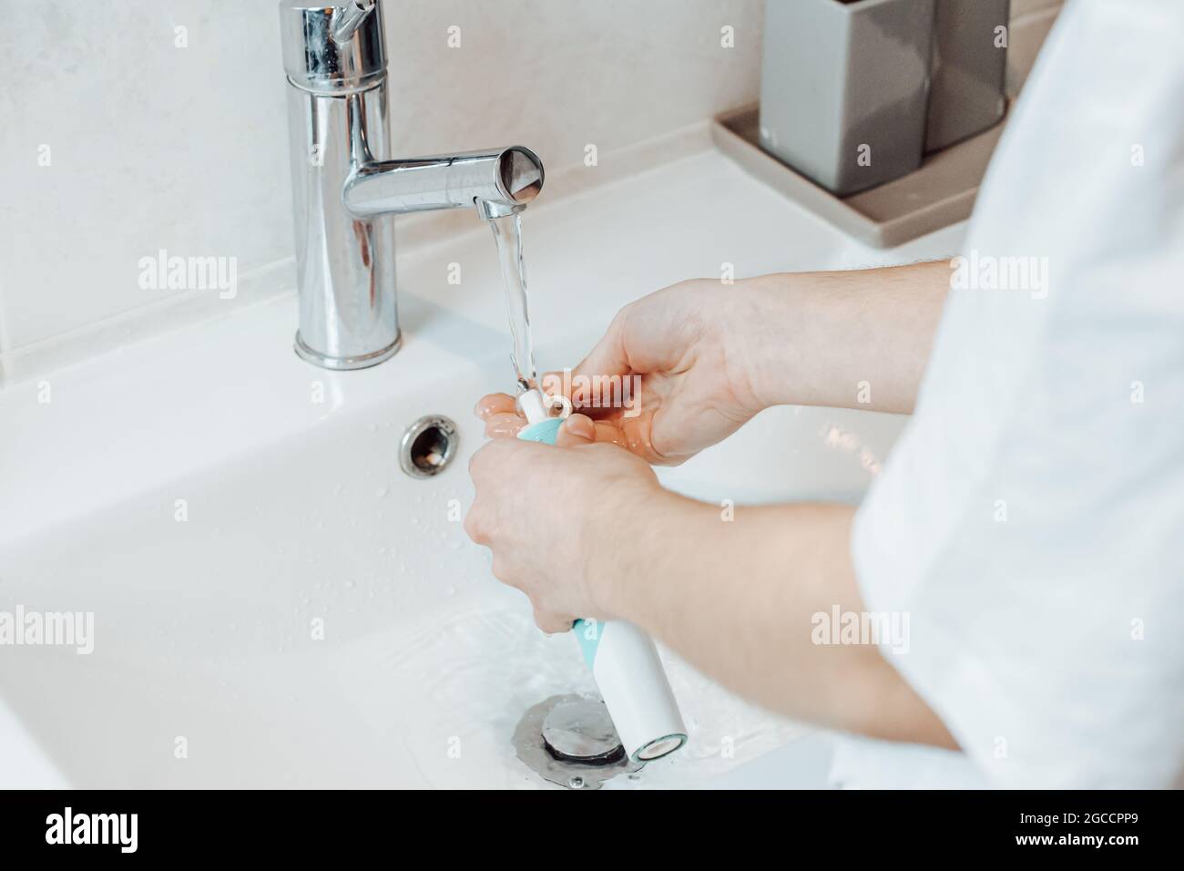 A high angle shot of female hands cleansing electric toothbrush under ...
