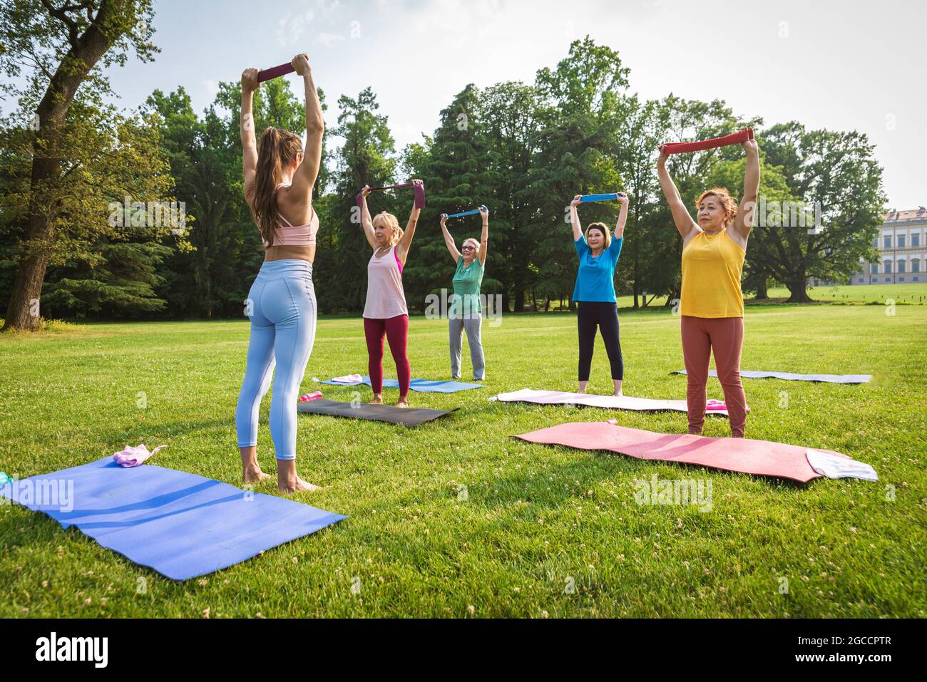 Multiethnic group of senior women training at park with fitness ...