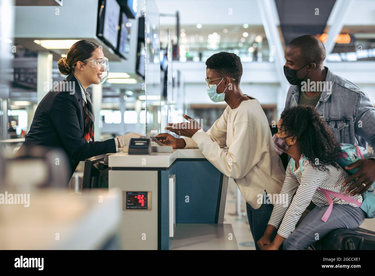 Passengers standing at check-in counter with airport staff during ...