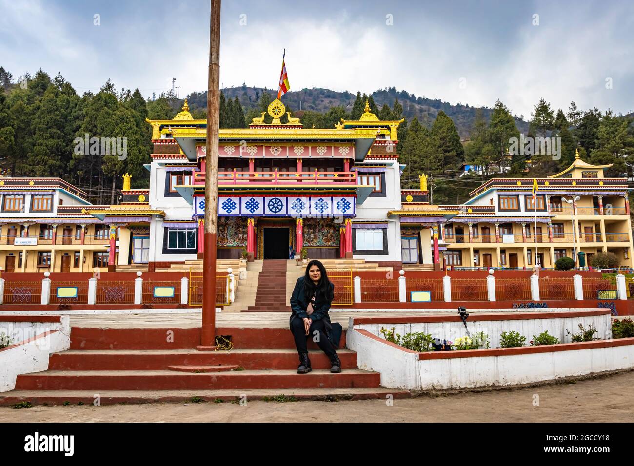 young girl sitting in front of ancient buddhist colorful monastery at ...