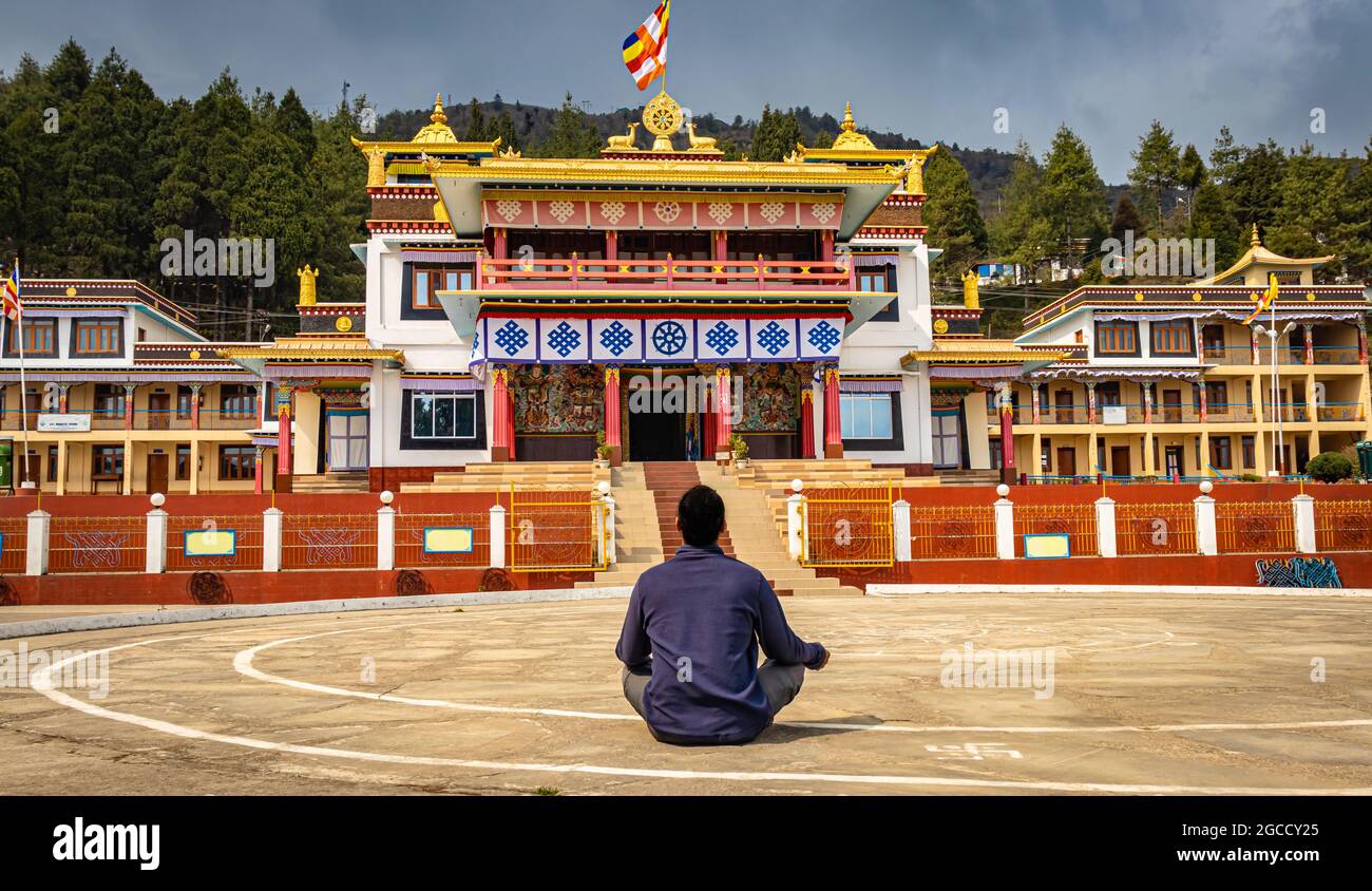 young man meditating in lotus position in front of ancient monastery at ...