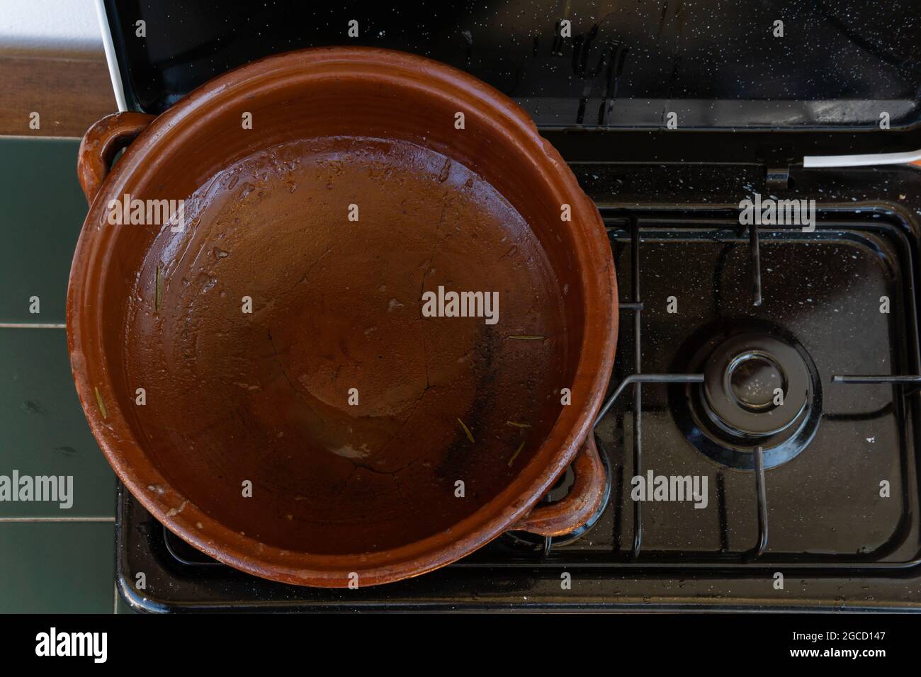 Empty earthenware casserole on an unlit gas stove. Culinary pottery ...