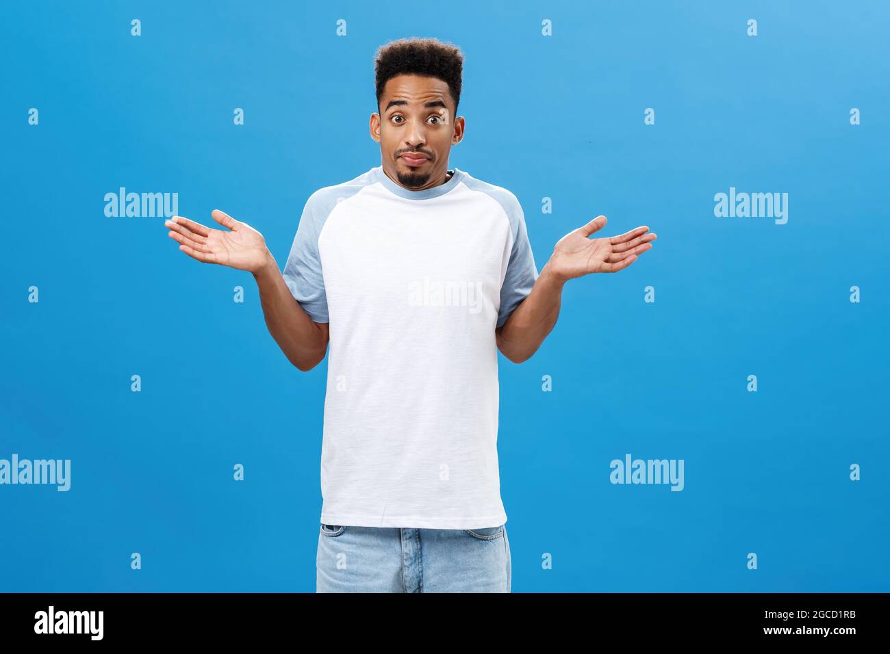 Studio shot of unaware clueless cute african american guy with beard ...
