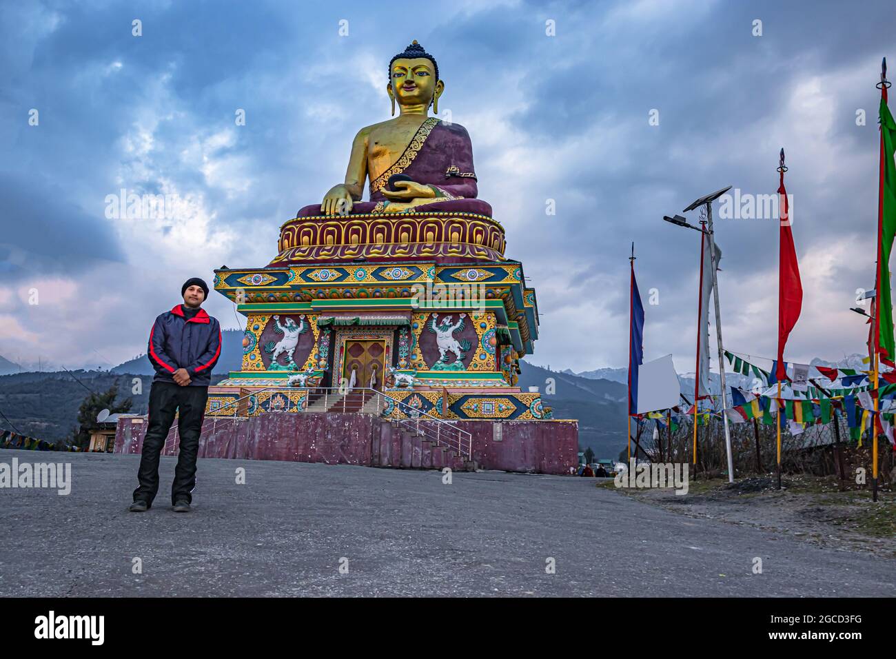 man standing near isolated huge buddha golden statue with moody sky at ...