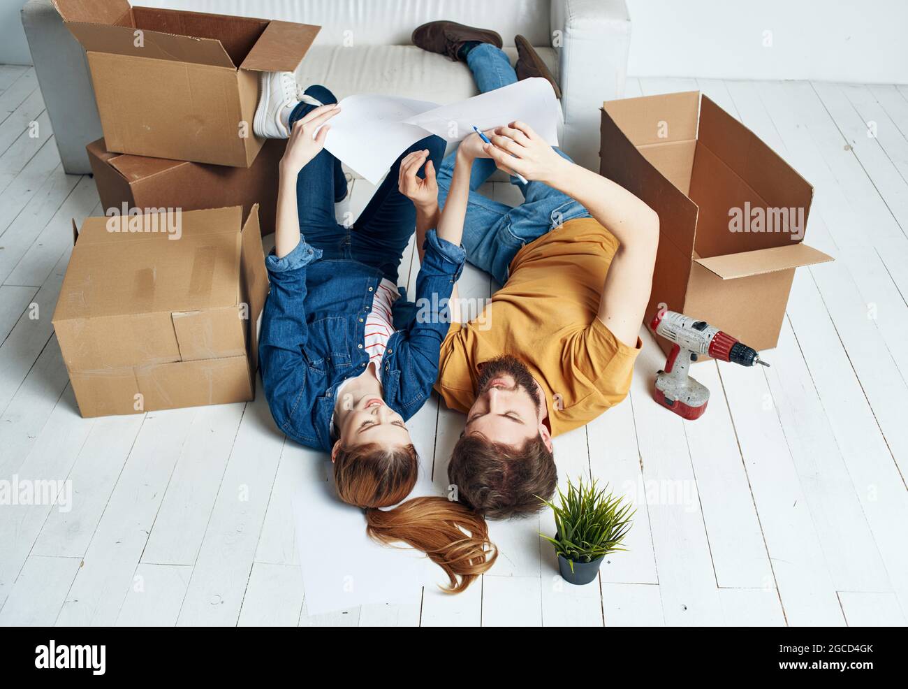 young couple lies on the floor with boxes home interior top view Stock ...