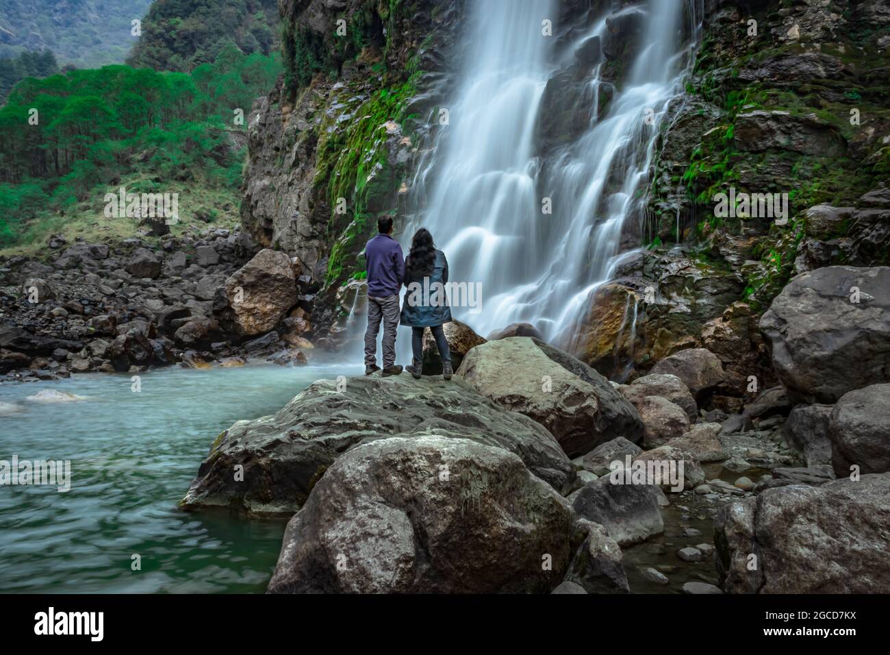 couple standing at rock in front of waterfall white water stream ...