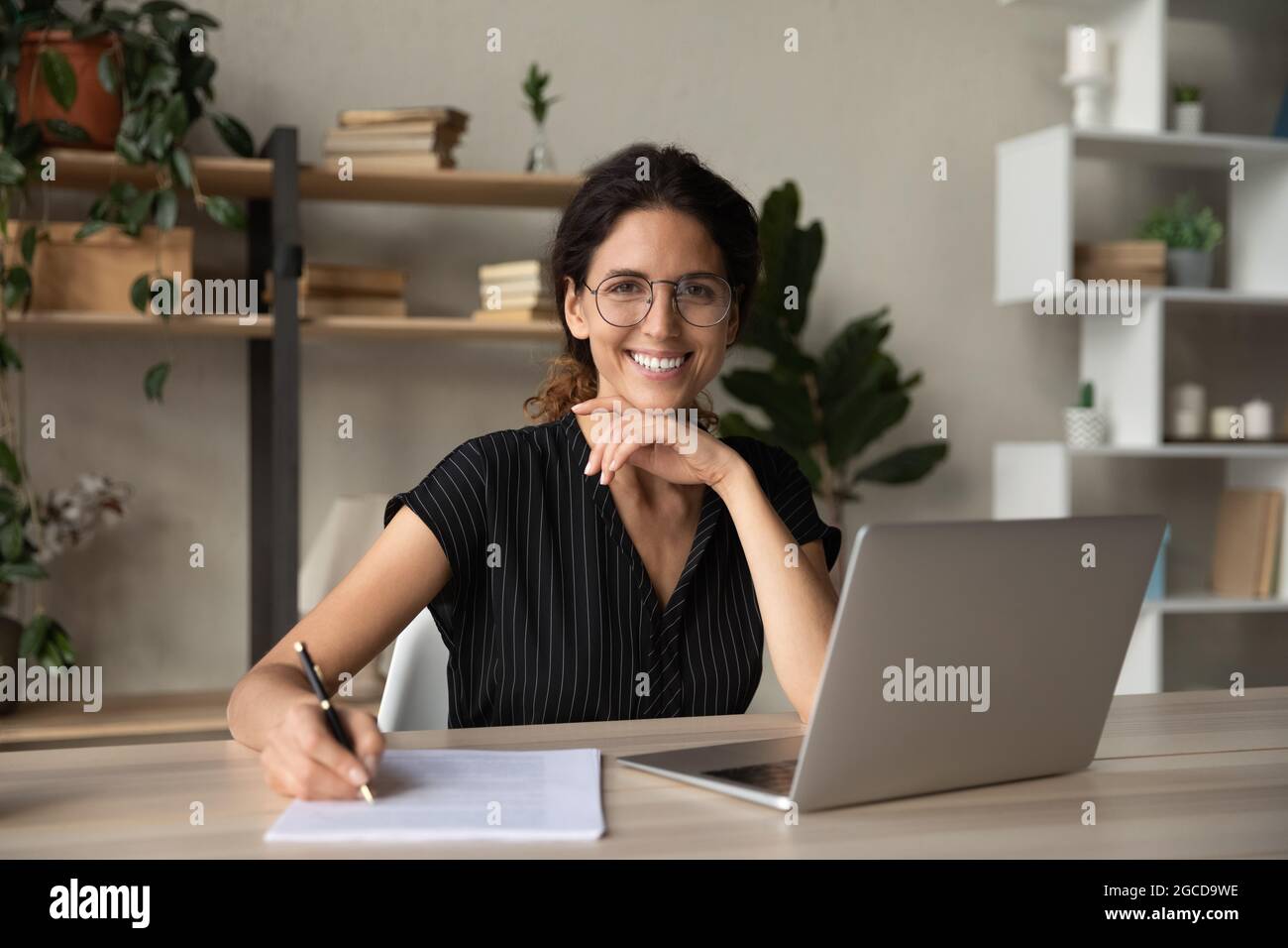 Head shot portrait of smiling woman in glasses taking notes Stock Photo ...