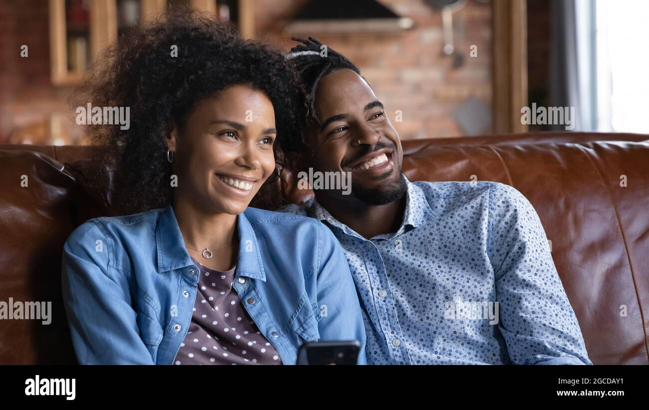 Happy ethnic couple rest on sofa dreaming visualizing Stock Photo - Alamy