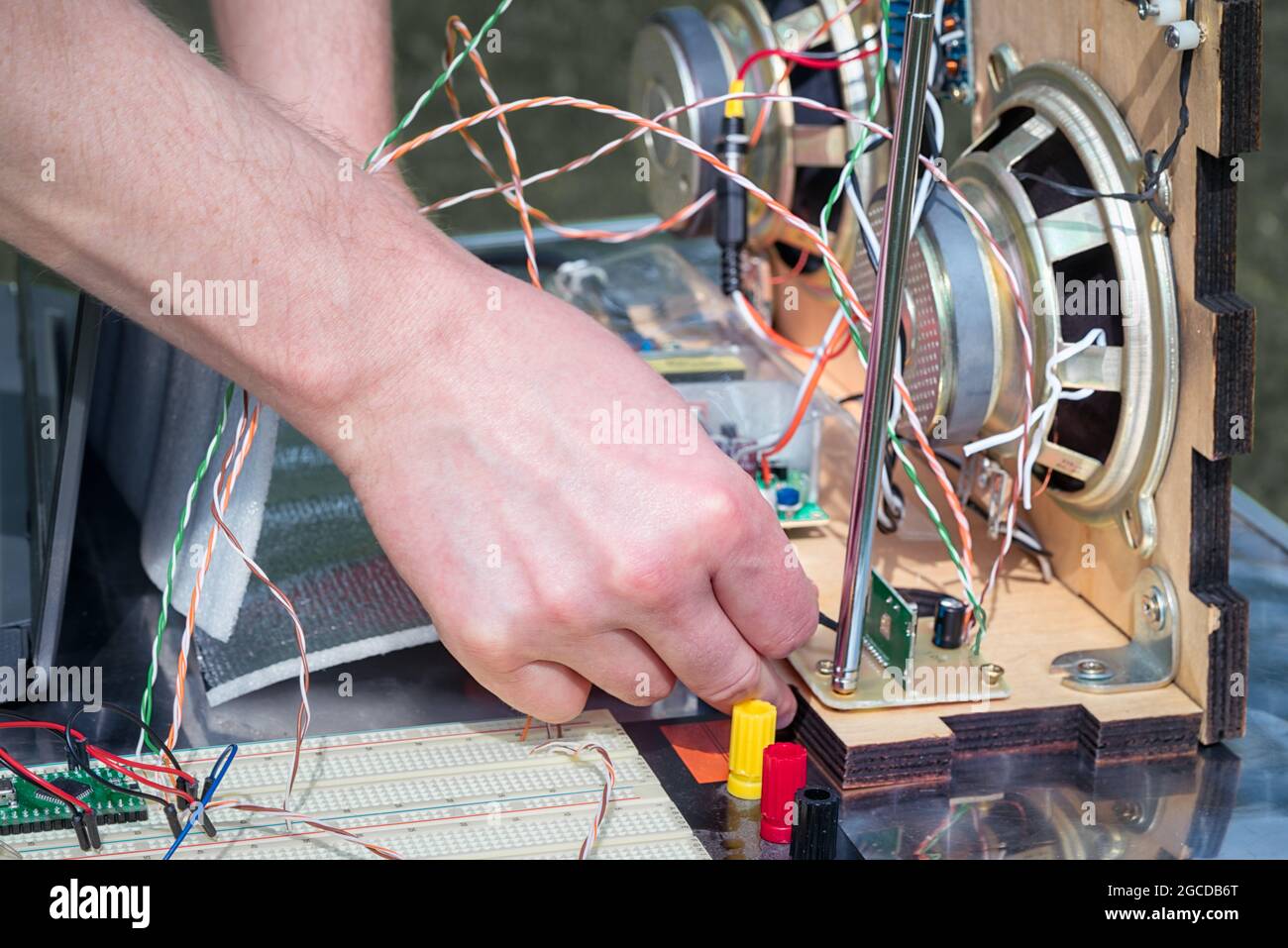 Hands connect wires and electronic contacts of homemade radio. Hobby of ...