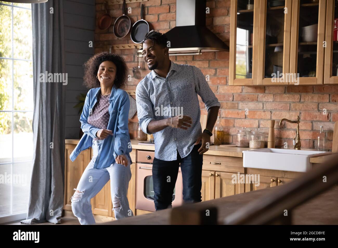 Happy young biracial couple dance together in kitchen Stock Photo - Alamy